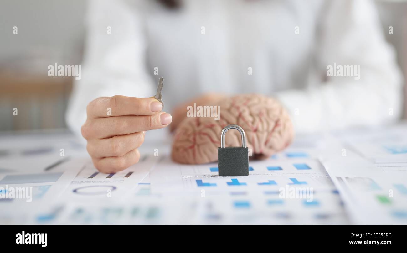 Woman hold key, lock and human brain on desk, symbol as key to someones ...