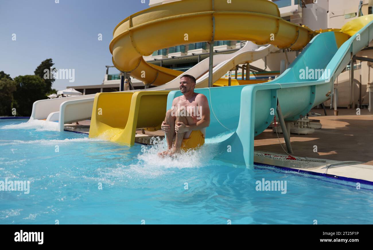 Middle aged man having fun, sliding at water park, summer vacation ...