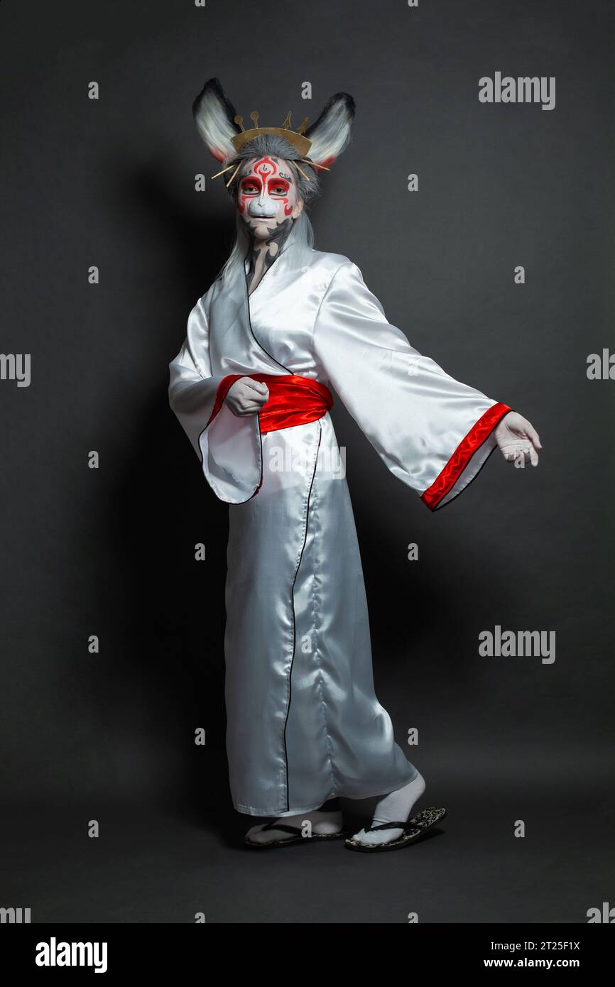 Perfect young woman wearing animal mask and white kimono standing on ...