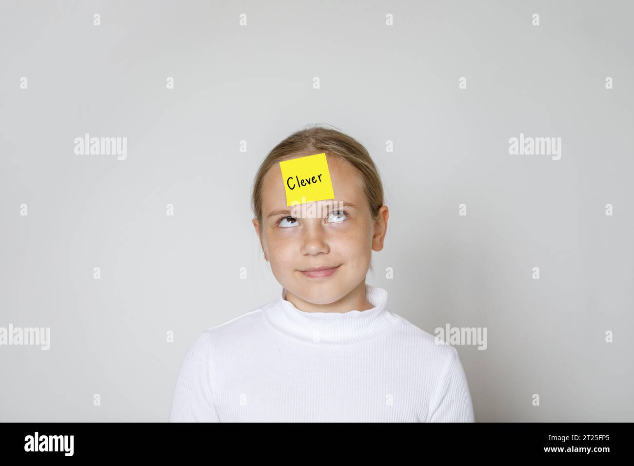 Clever kid young girl with yellow sticky note paper against white ...