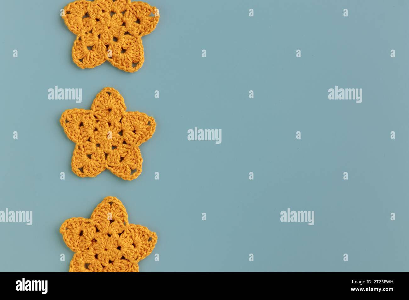 Three yellow crocheted stars row pattern on a blue background Stock ...