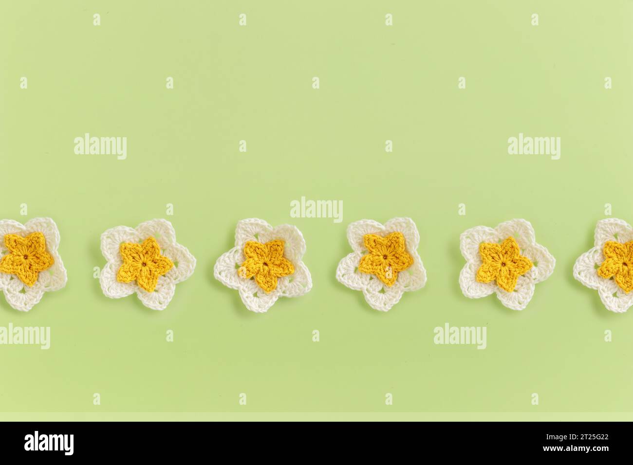 Yellow crocheted flowers row pattern on a green background Stock Photo ...