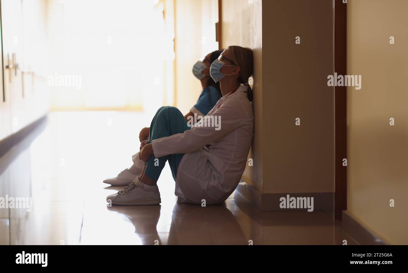 Exhausted nurses after hard long surgery sitting on floor in hall ...