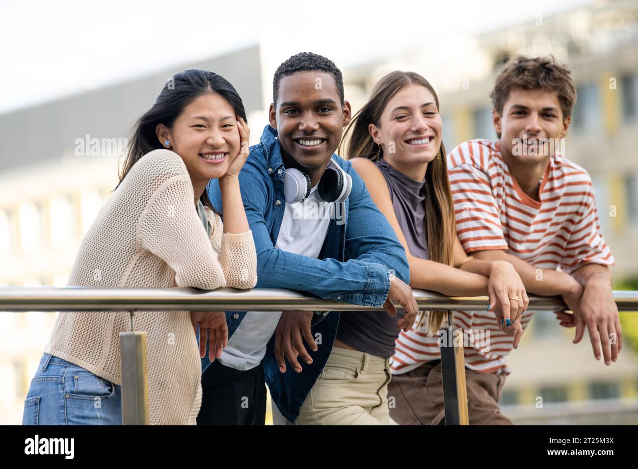 Beautiful young men and women smiling and looking at camera leaning on ...