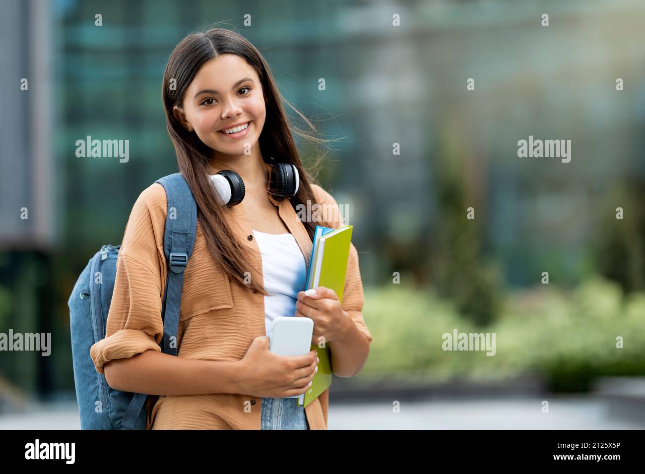 Smiling student holding books, posing at university Stock Photo - Alamy