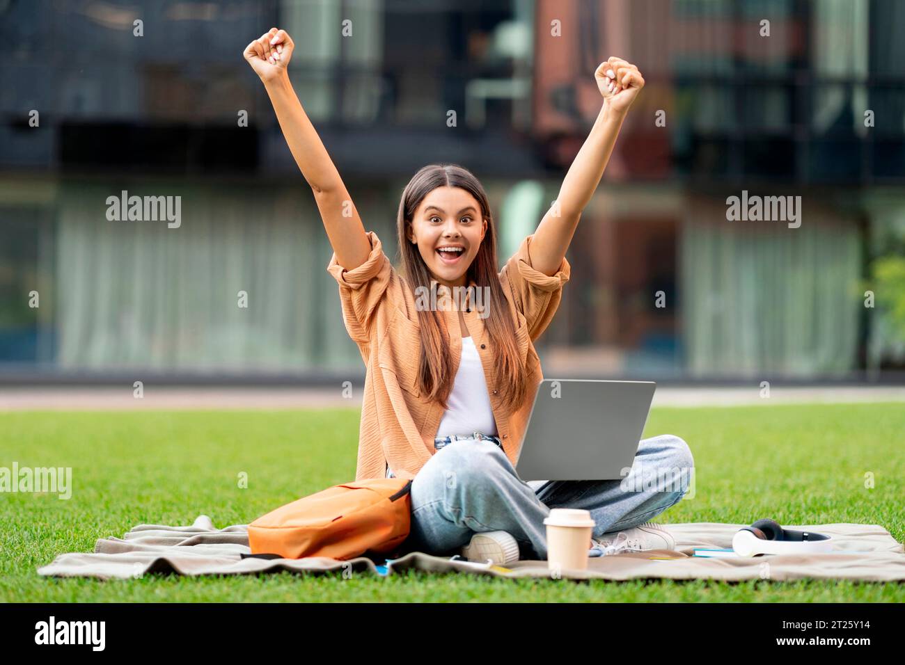 Emotional woman student with laptop on lap raising hands up Stock Photo ...