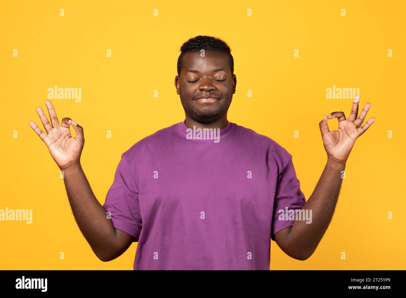 Calm african guy doing meditation with om gesture, yellow background ...