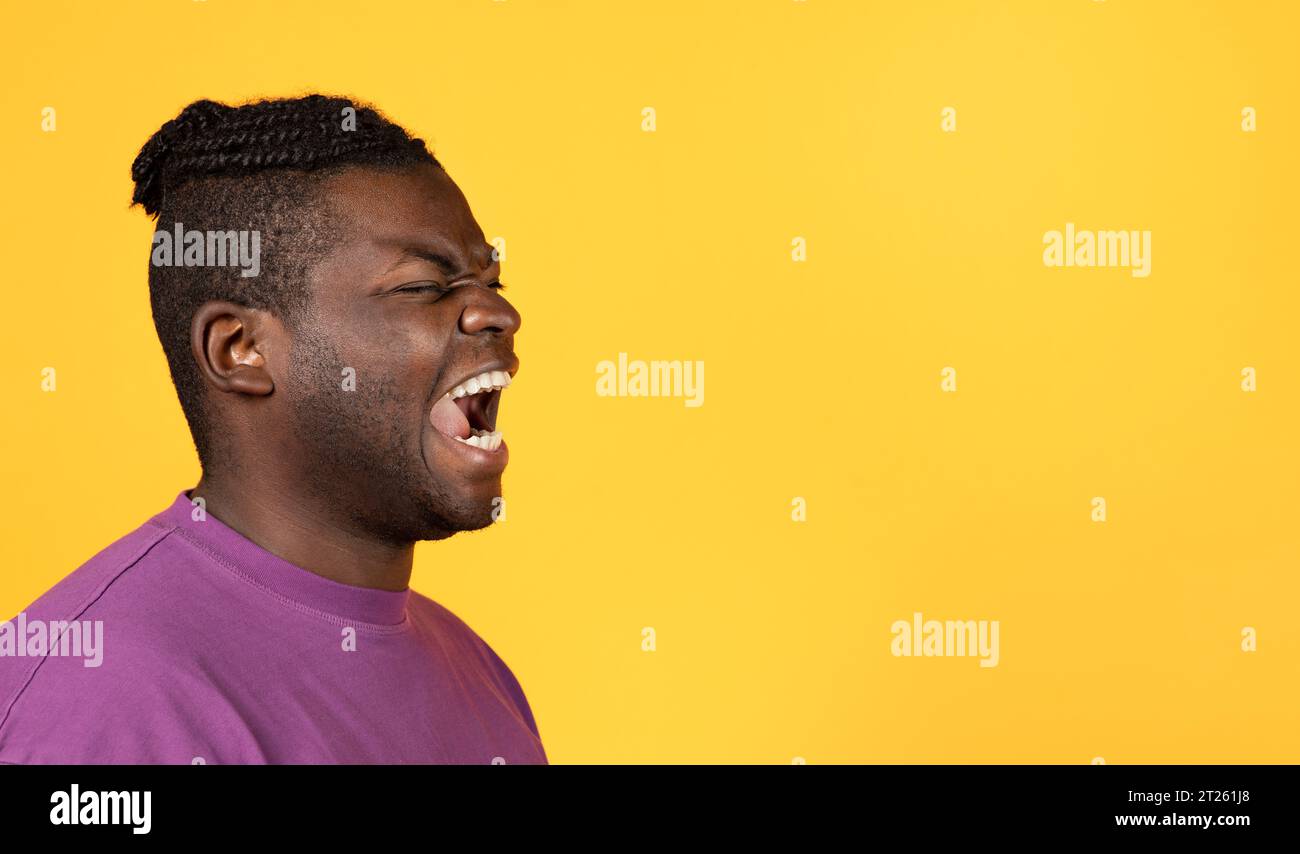 Angry black man shouting towards free space over yellow background ...