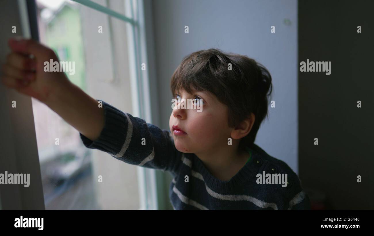 One little boy holding window knob wanting to open window from ...
