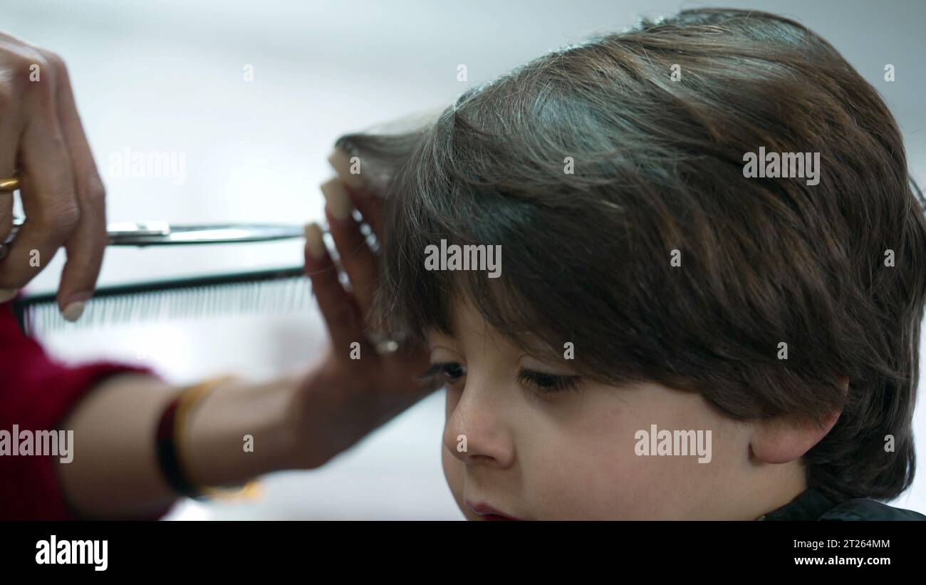 Child getting a haircut at hair salon. Professional hairstylist cutting ...