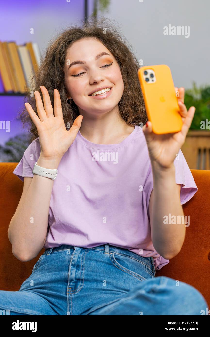 Young woman making phone call conversation with friends sitting on sofa ...