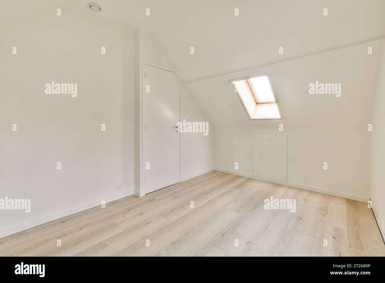 an empty room with white walls and wood flooring, there is a skylight ...