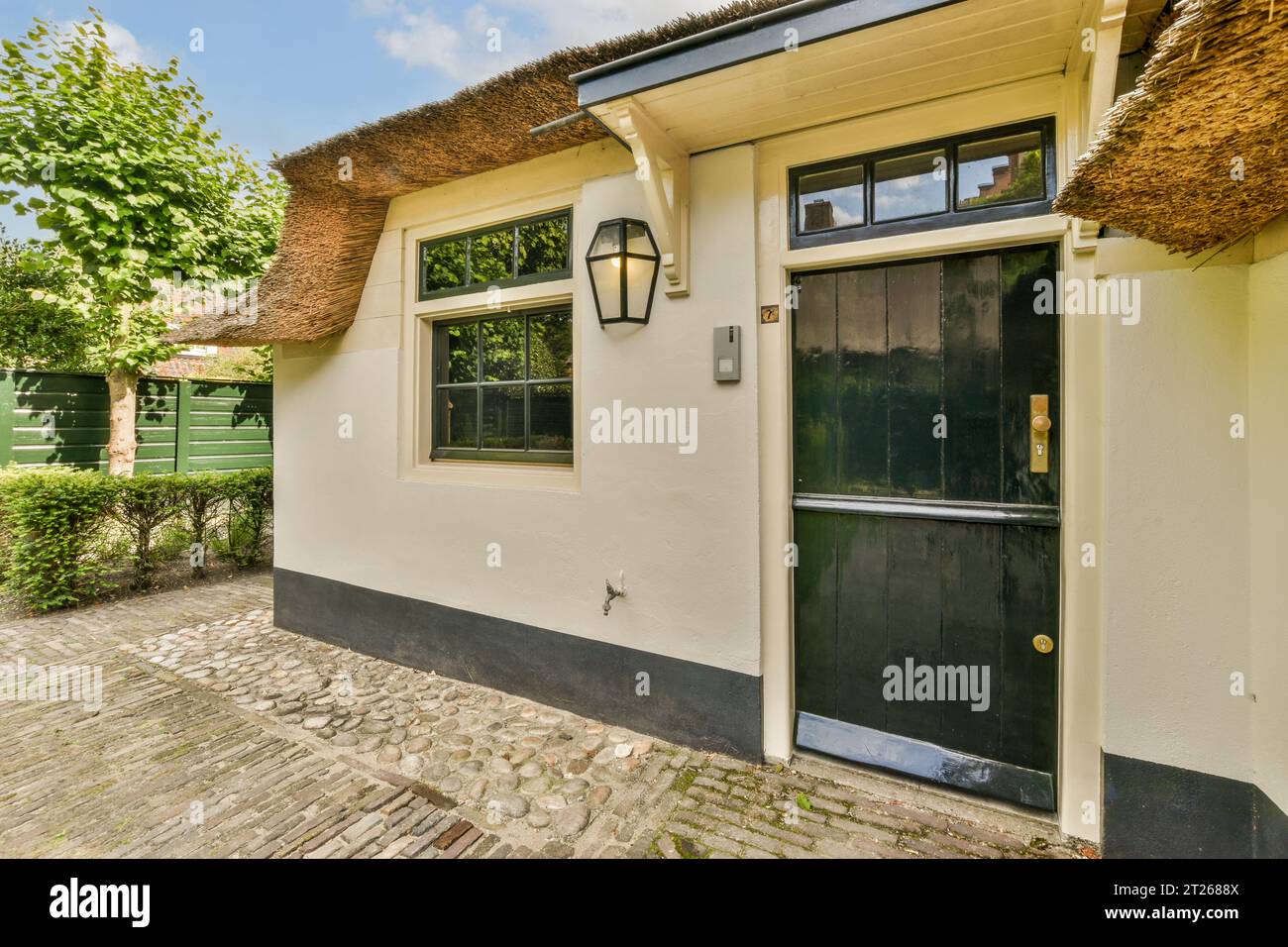 the outside of a house with thatched roof and black door, in front of ...