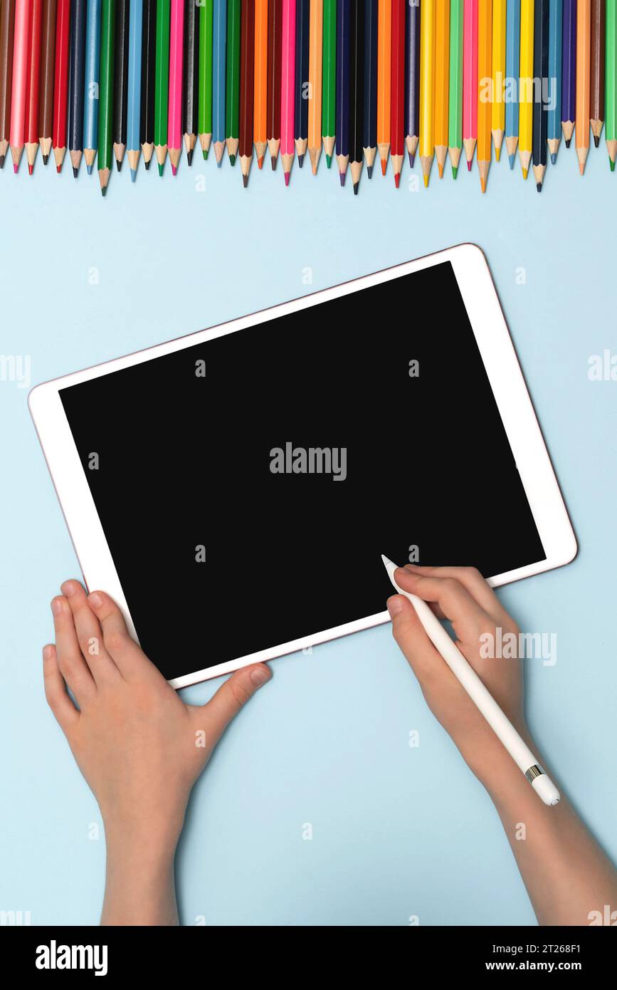 Child drawing on tablet. Colorful pencils and tablet on blue background ...