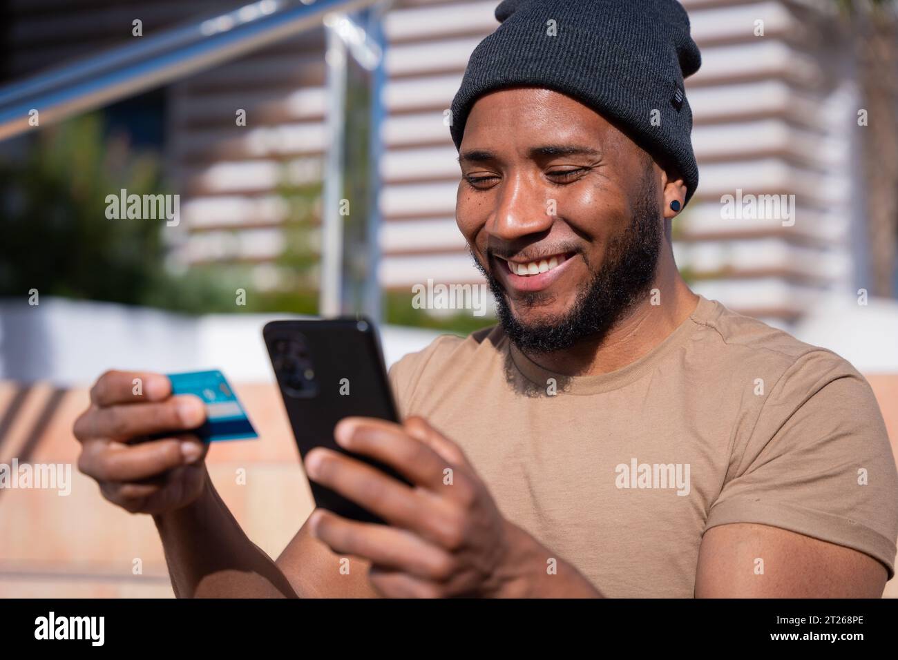 Happy young black man with credit card and smartphone Stock Photo - Alamy