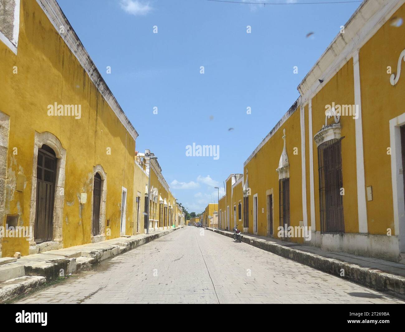 An idyllic street scene featuring rows of sunny yellow buildings with ...