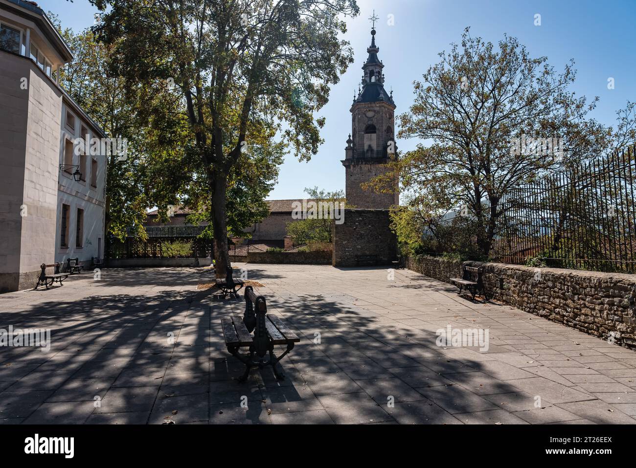 Park with benches and tower of the old church of the monumental city of ...