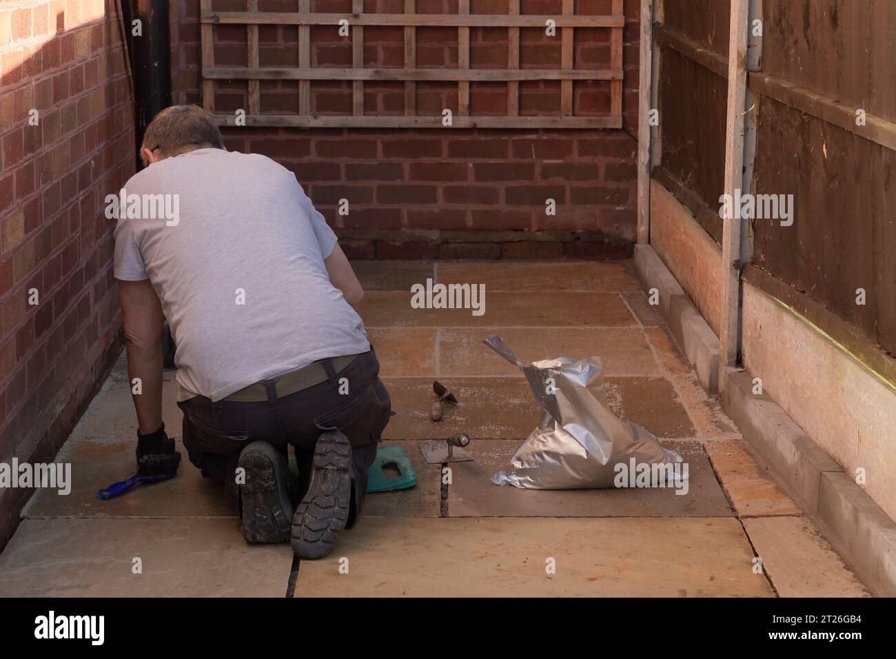 Builder knealing down and filling in the cracks on a pavement Stock ...