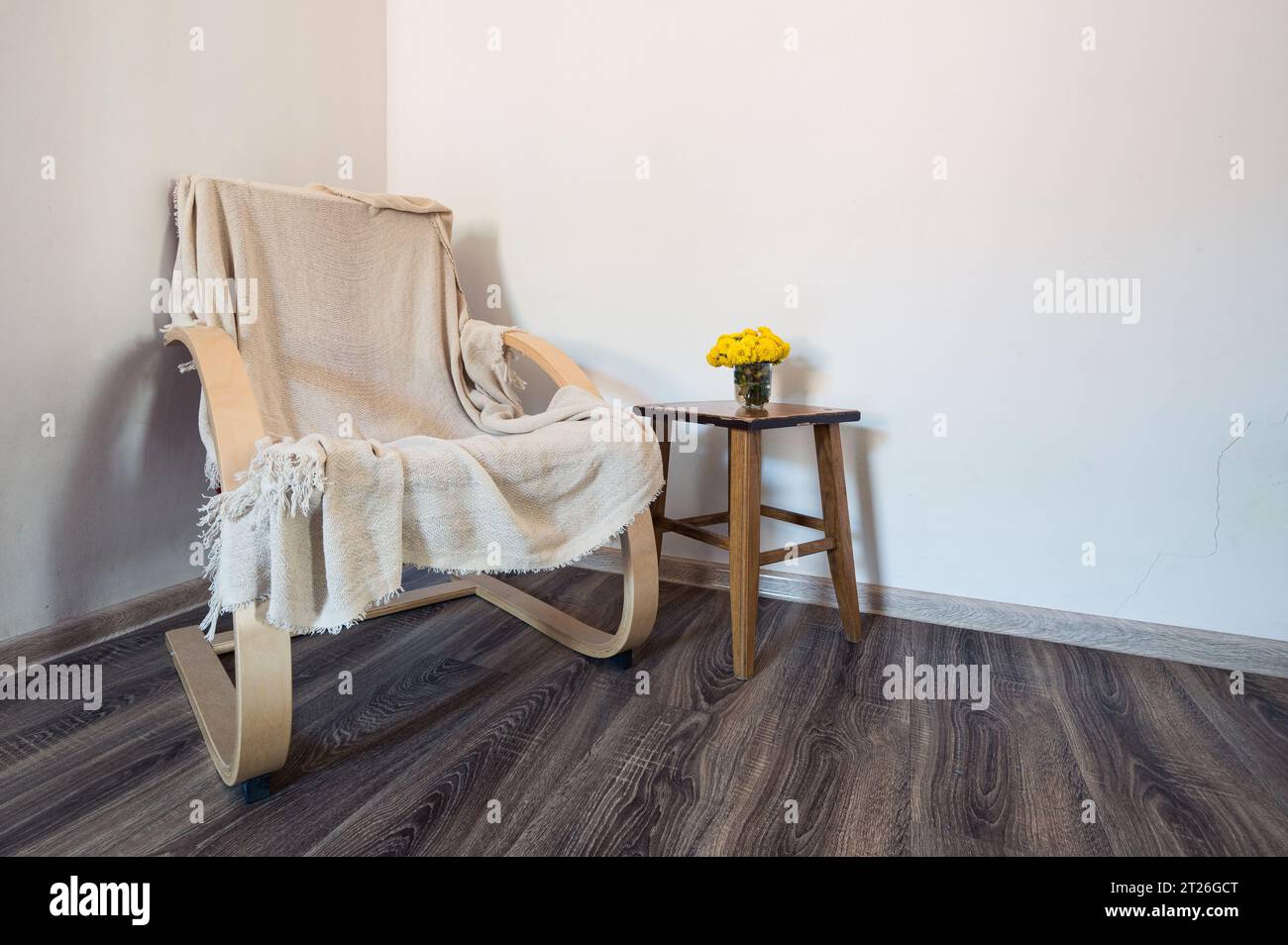 Wooden modern armchair cowered with cotton plaid and vase of yellow ...