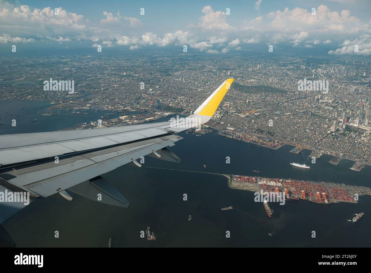 Wing from window of airplane flying over the city of Manila. Aerial ...