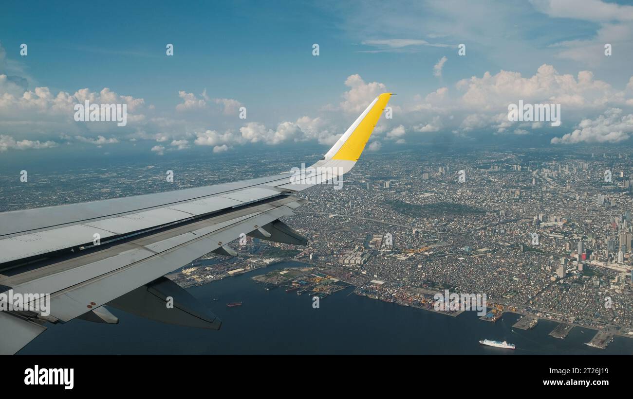 Wing from window of airplane flying over the city of Manila. Aerial ...