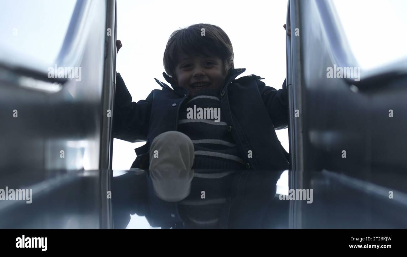 Autumn Playground Delight/ Kid Sliding with a Smile, Child in Jacket ...
