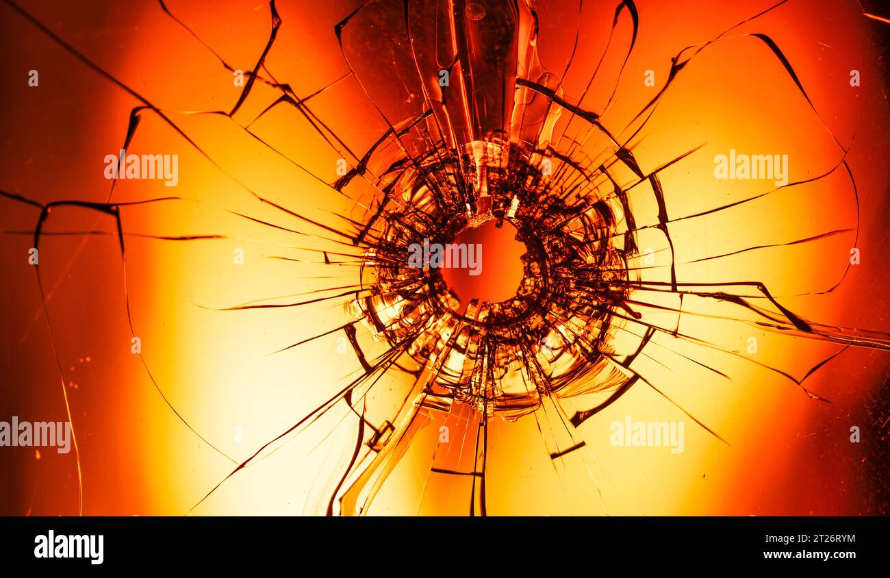The Torn Veil: A Bullet's Mark on Glass Amid an Infern Stock Photo - Alamy