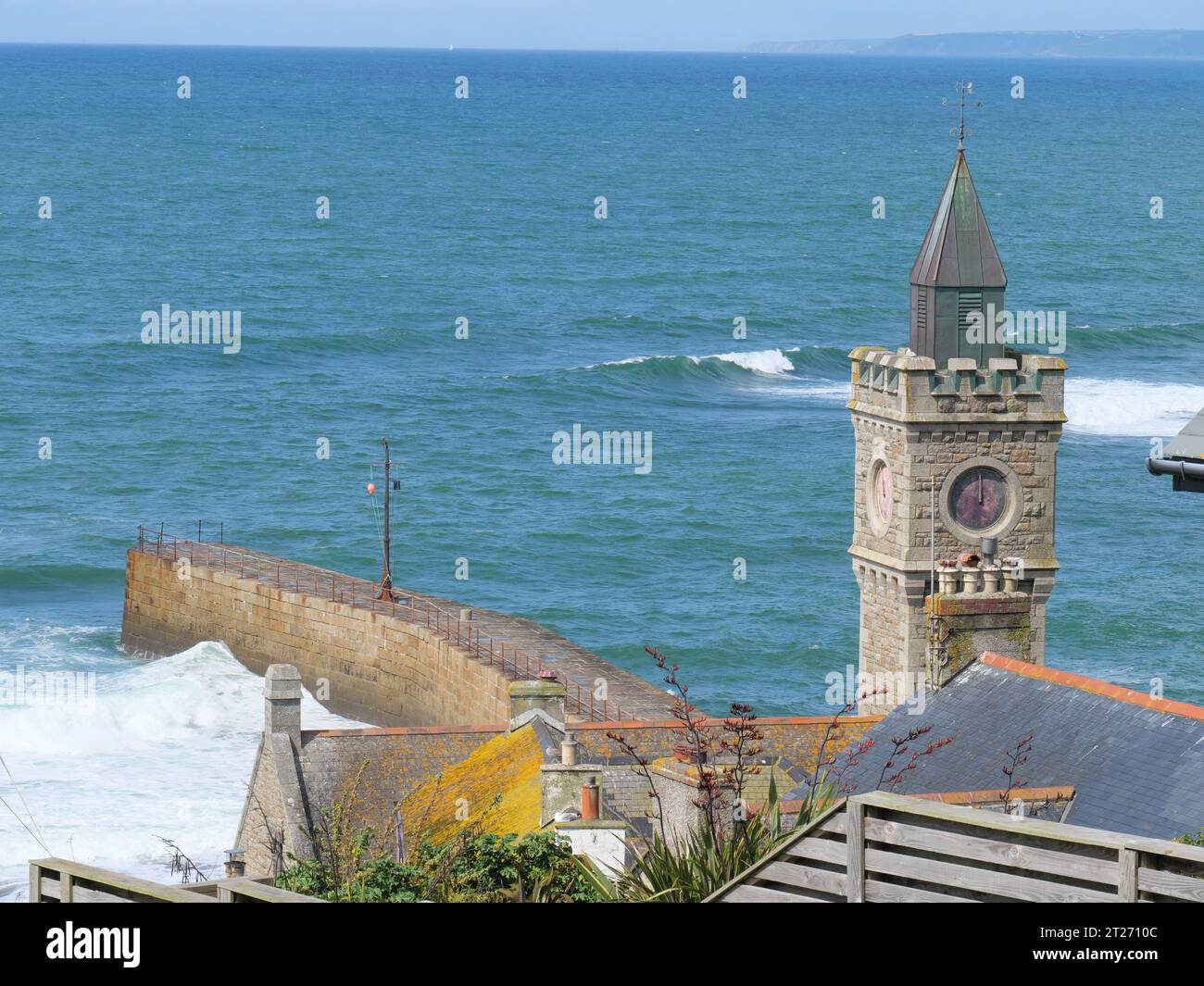 View of a clock tower and pier from a hill on the harbor of Porthleven ...
