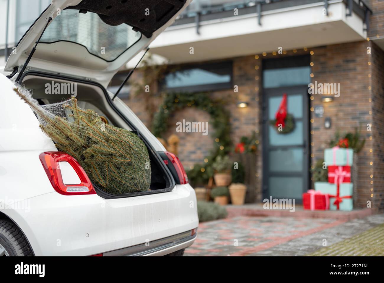 Christmas tree in vehicle trunk in front of a house decorated for ...