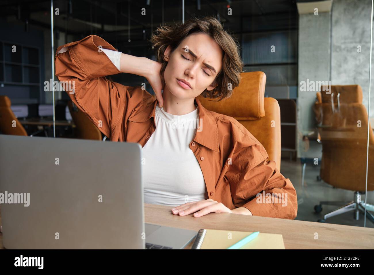 Image of woman with tired face, sits with laptop in office, feels ...
