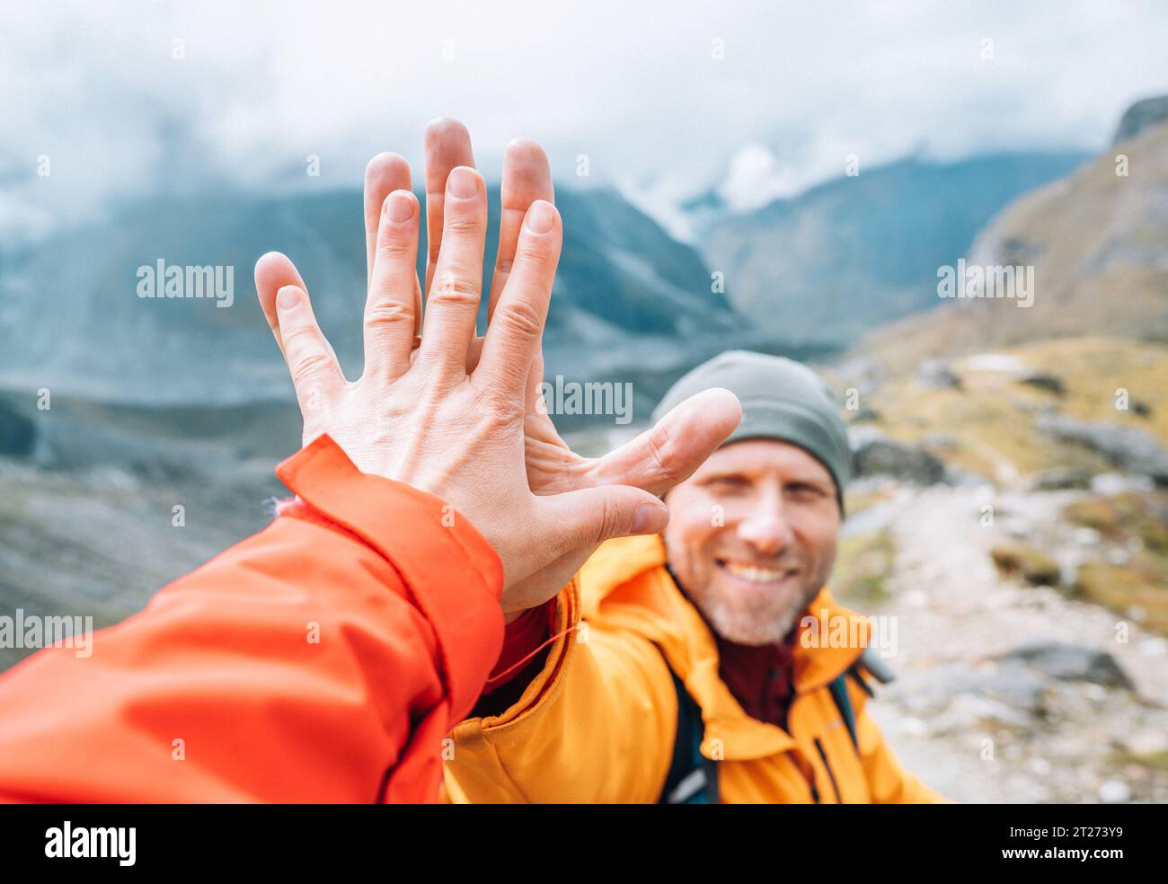 Smiling backpacker dressed orange jacket giving High Five to female ...