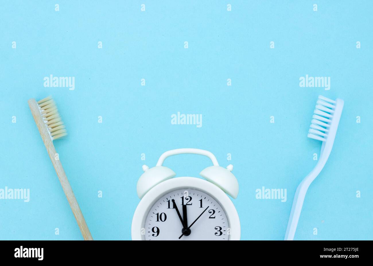 Alarm clock, toothbrushes on light blue background. Healthy teeth ...