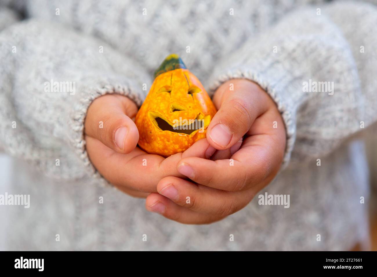 9 September 2023: A child holding small Halloween pumpkin with mean ...