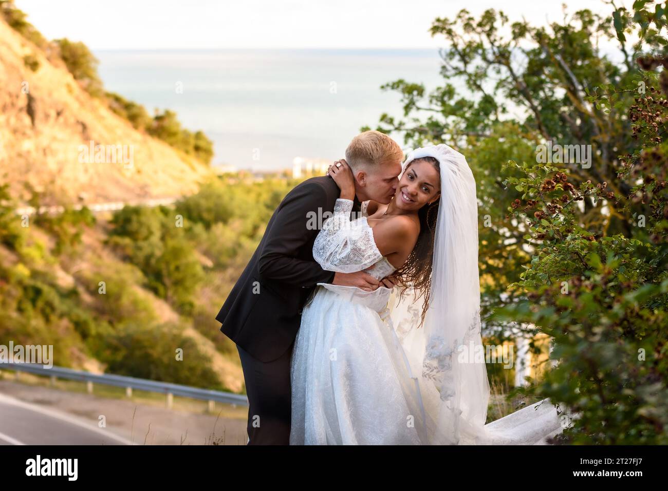 Happy newlyweds kiss against the backdrop of a beautiful mountain ...