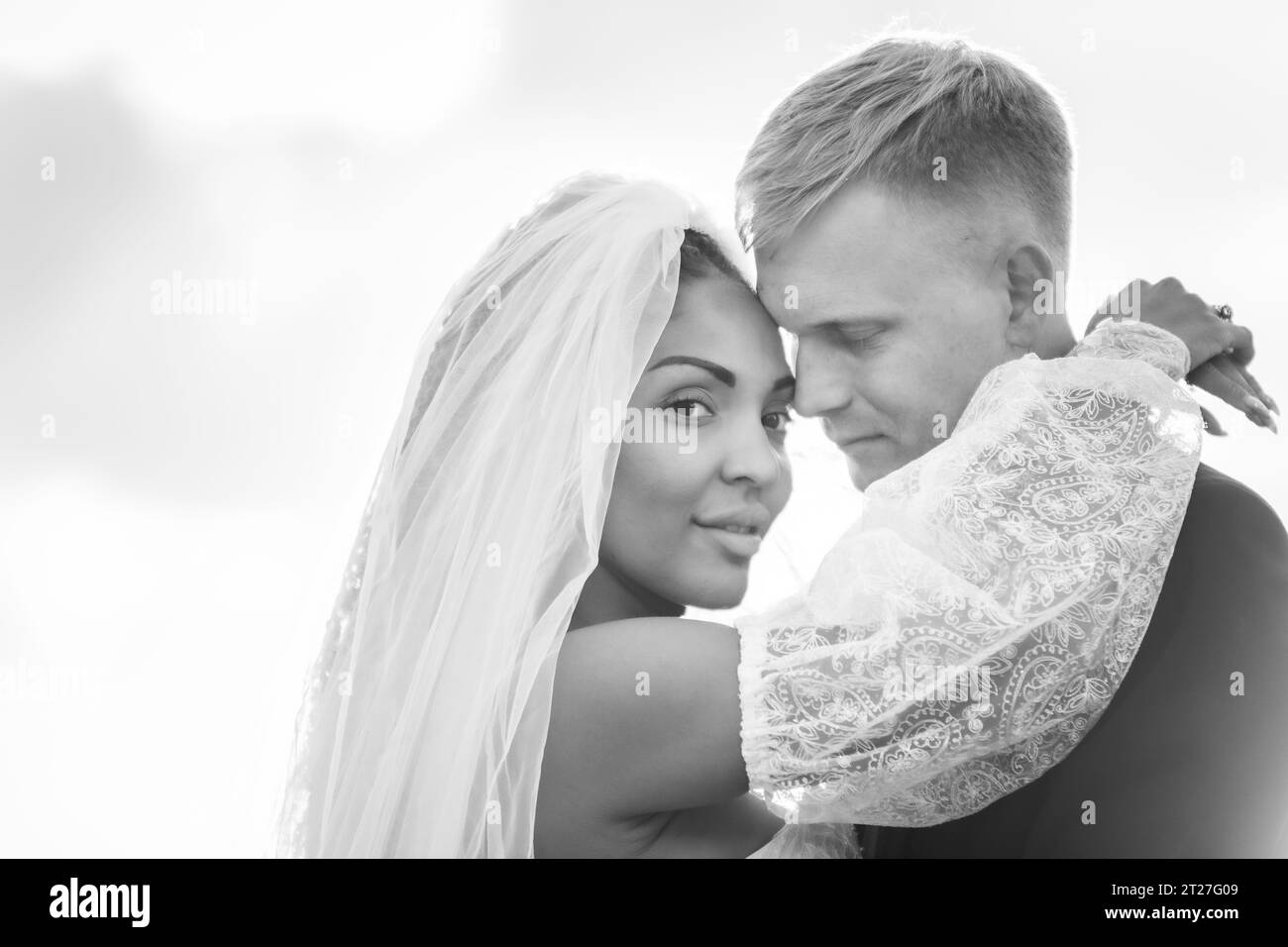 Happy newlyweds hugging in the rays of the setting sun, black and white ...