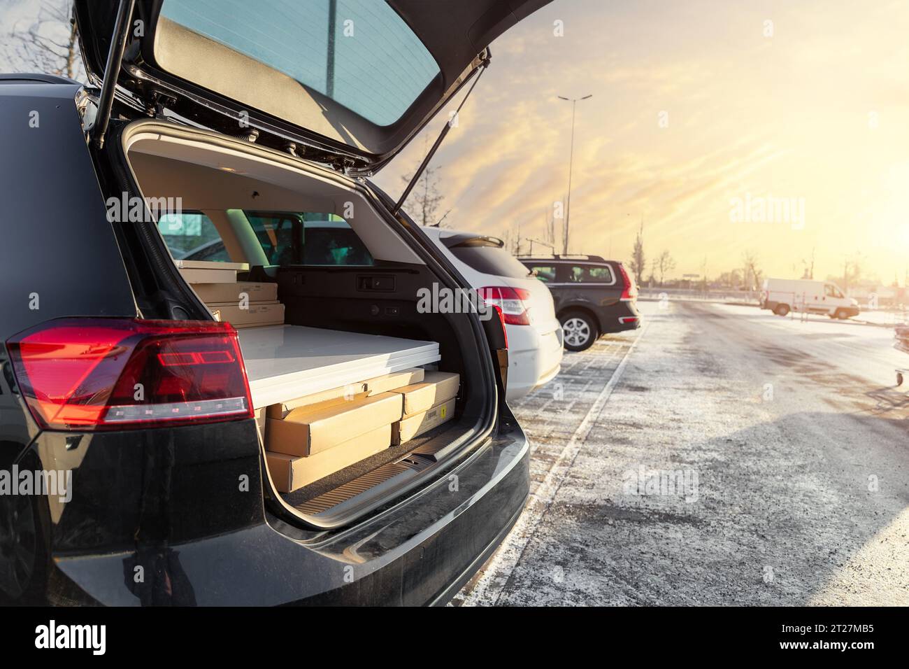 Modern black car wagon with open boot trunk back door fully loaded with ...