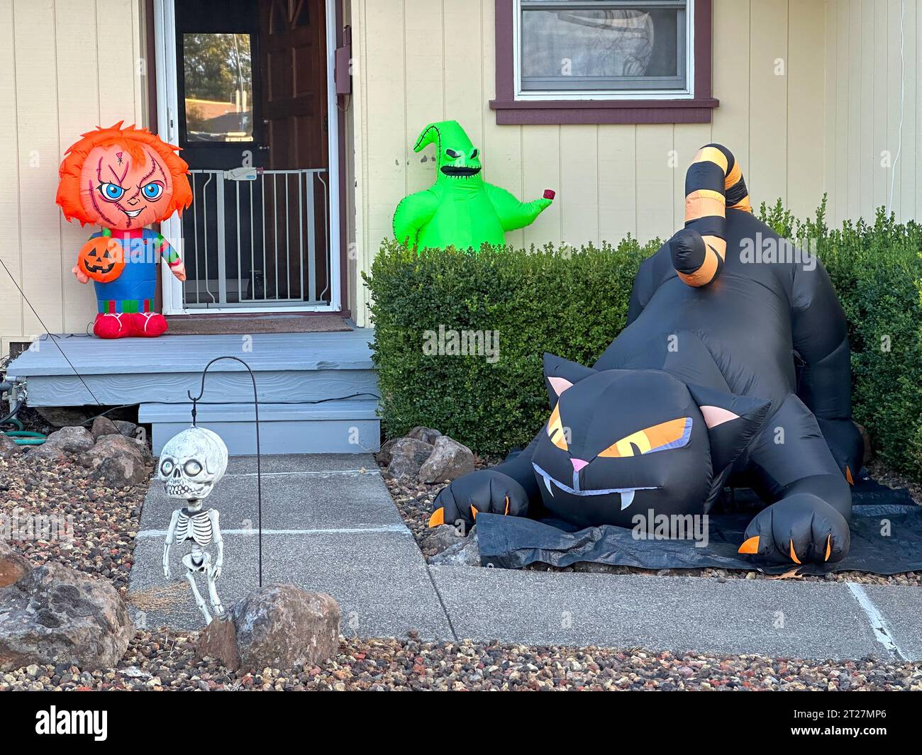 A yard has Halloween decorations that include a green monster, an ...