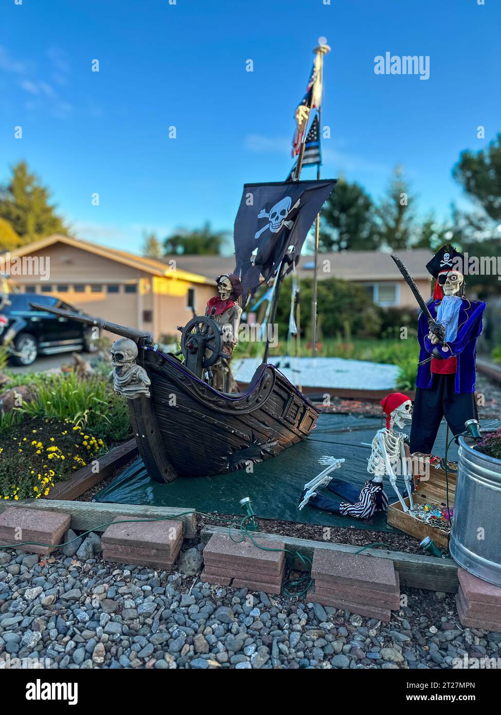 A yard has halloween decorations that include a pirate ship, pirate and ...
