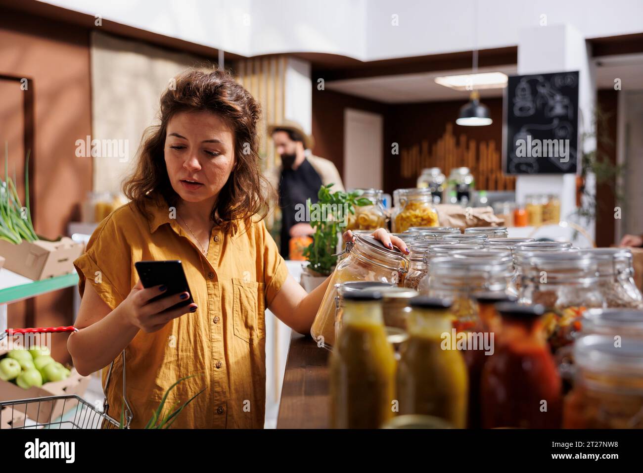 Woman in local groceries store using smartphone notes app to check ...