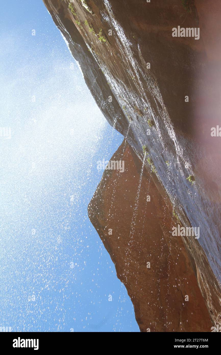 A person in a wetsuit, surfboard in hand, riding a wave in a wave pool ...