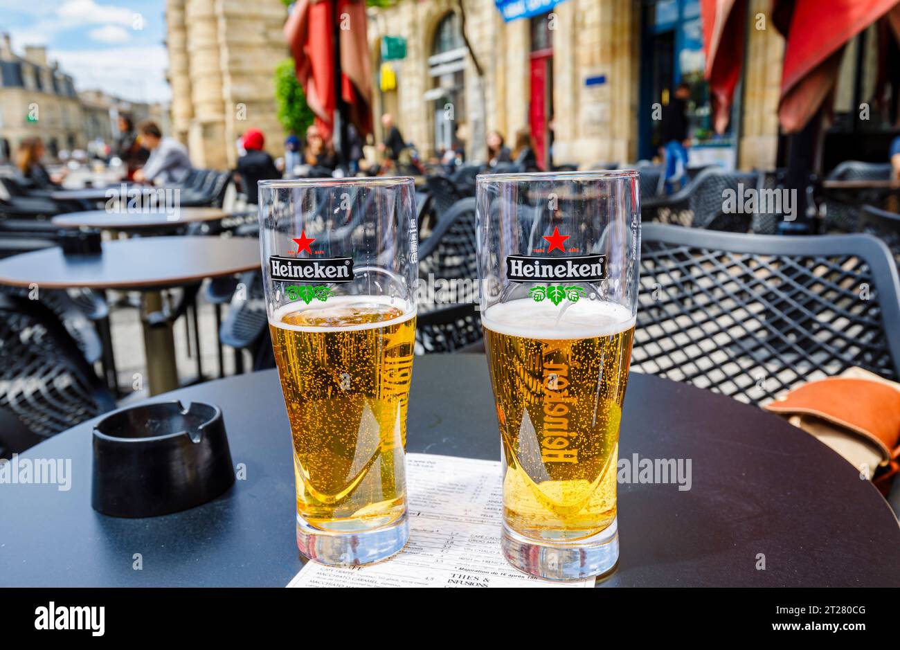 Two half full Heineken badged beer glasses on a table top in a cafe bar ...