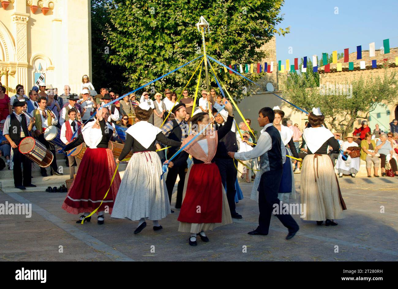 Young men and women in Provençal costume dancing around a maypole to ...