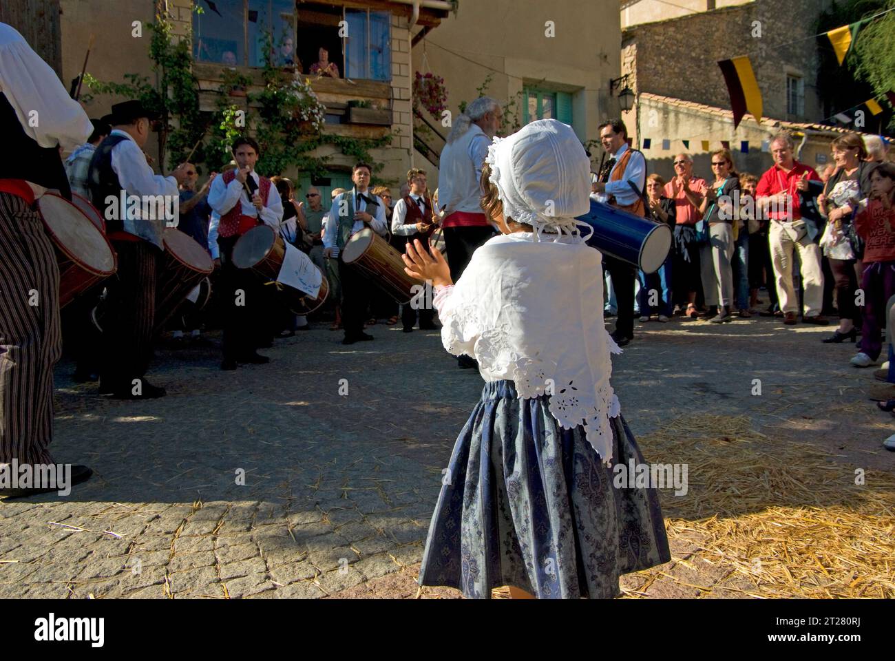 Small girl in local costume clapping hands while watching provençal ...