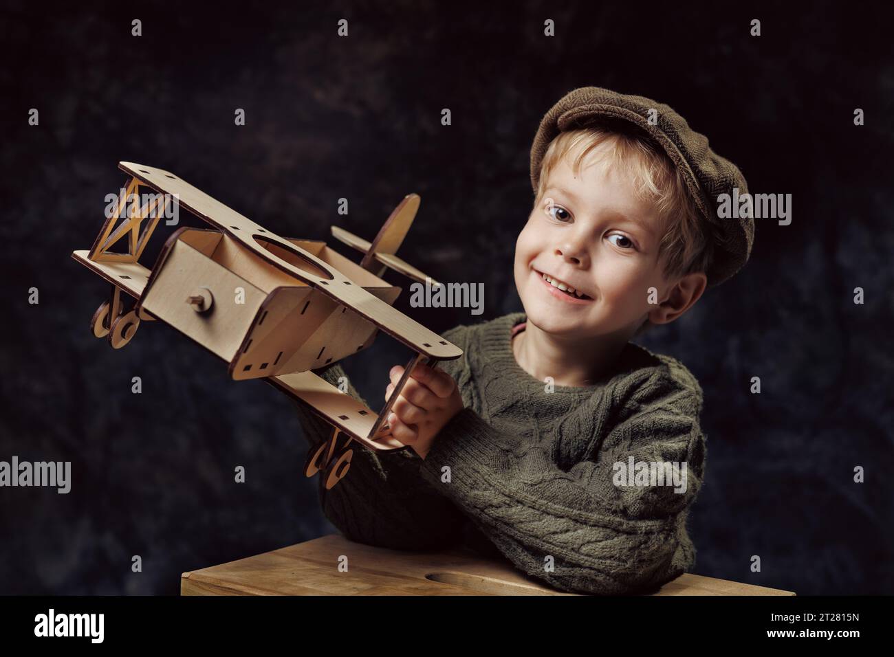 A child, a toddler boy, plays with a toy airplane and dreams of ...