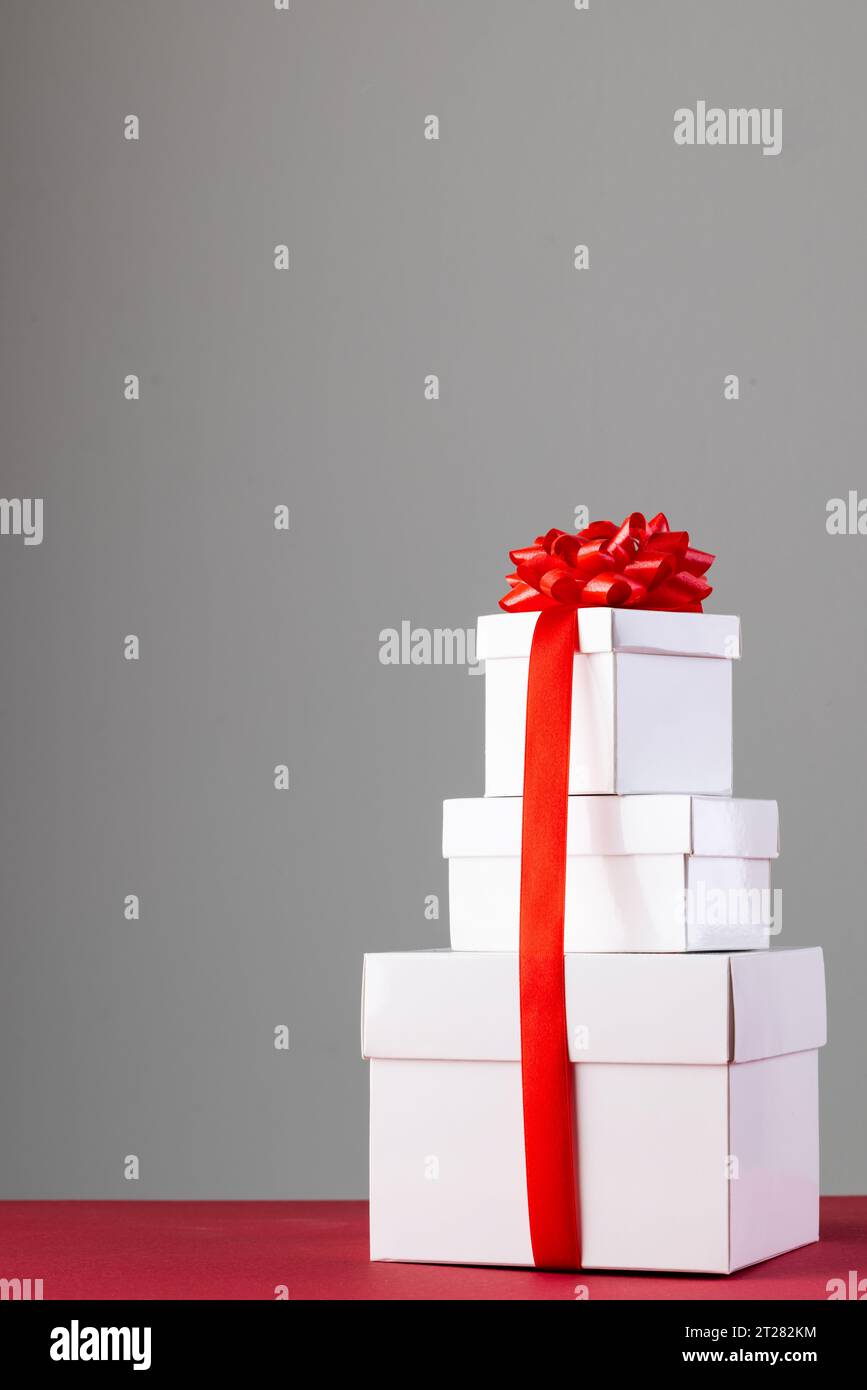 Vertical image of stack of christmas presents with red ribbon and copy ...