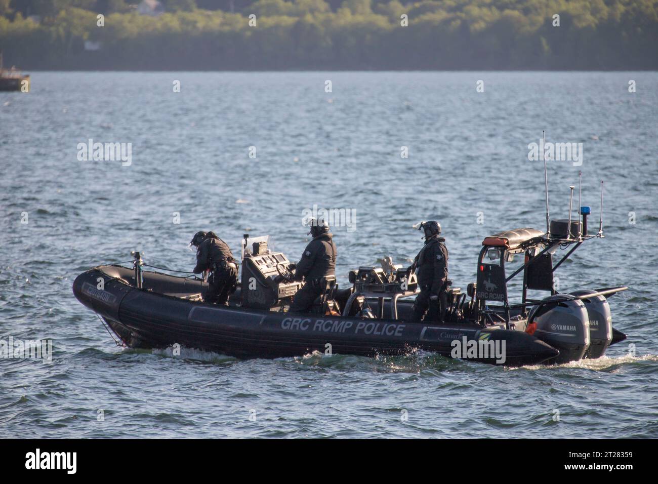 A group of police officers on a RCMP boat patrol the shoreline of a ...