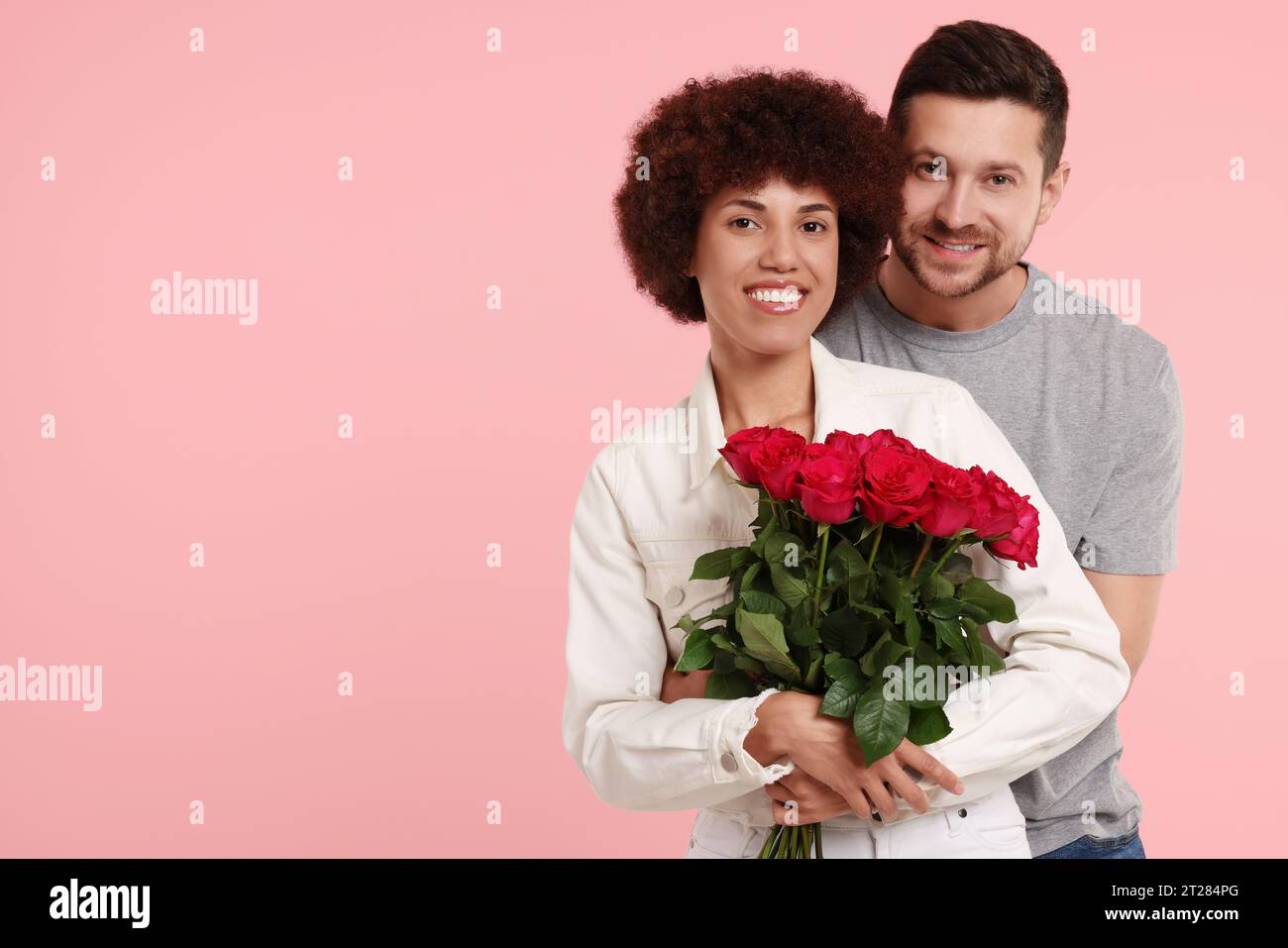 International dating. Lovely couple with bouquet of roses on pink ...