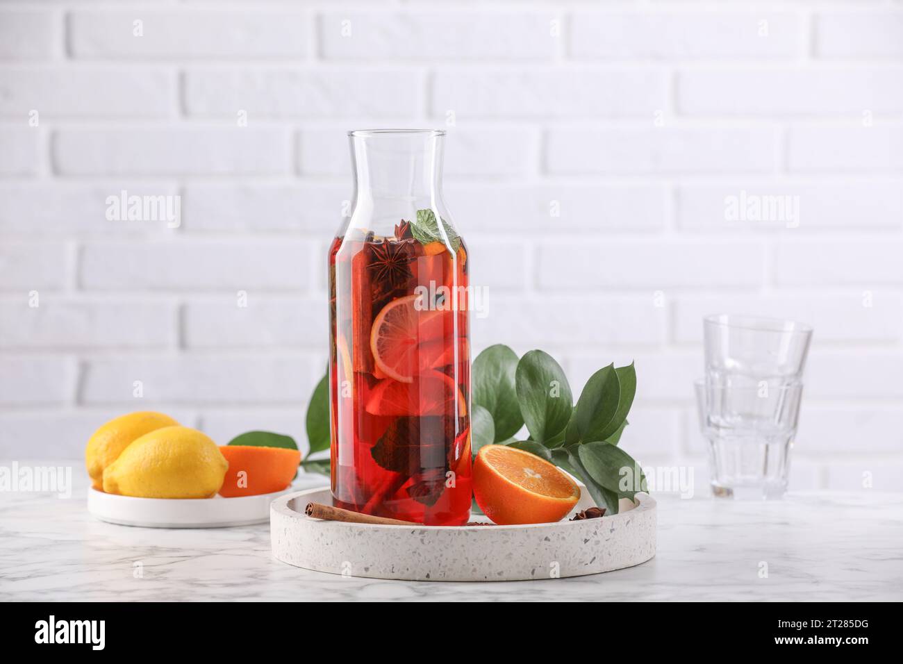 Delicious punch drink in bottle and ingredients on white marble table ...