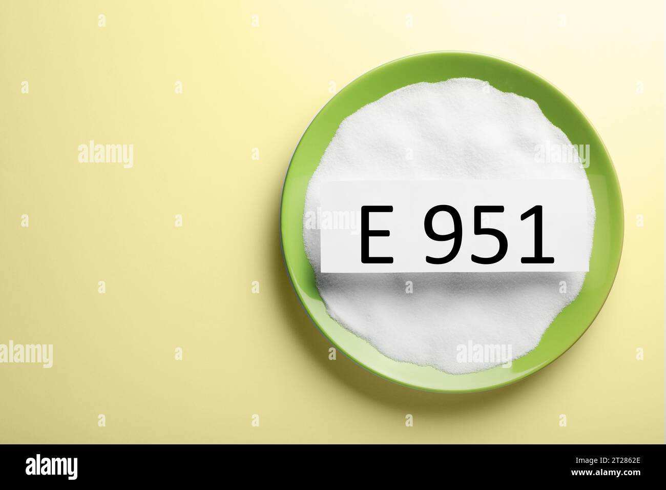 Card with aspartame code (E951) and artificial sweetener in bowl on ...