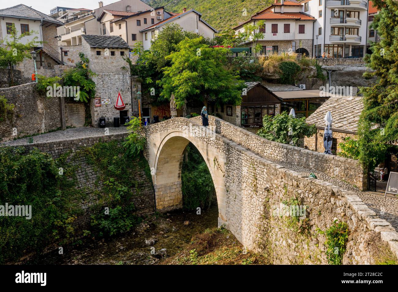 A Muslim woman is walking over the Kriva Cuprija (Crooked Bridge) over ...